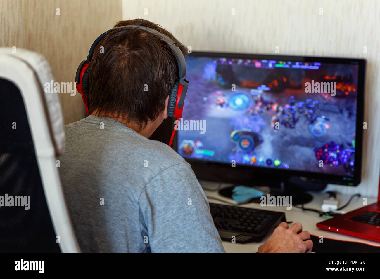 Back view of concentrated young gamer in headphones using computer for ...