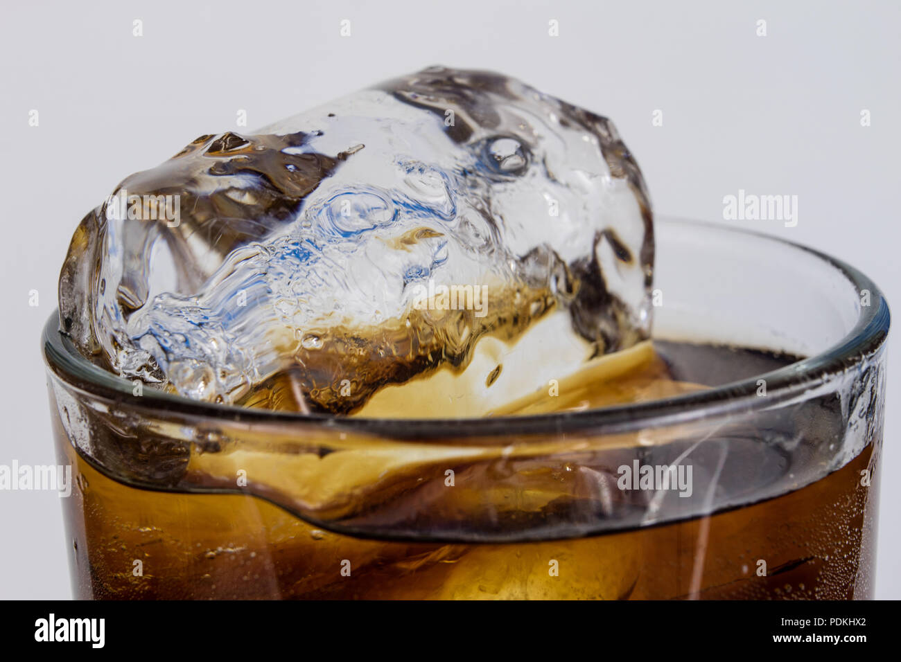 Cold drink with ice in a glass on a white table. A way to cool down on ...