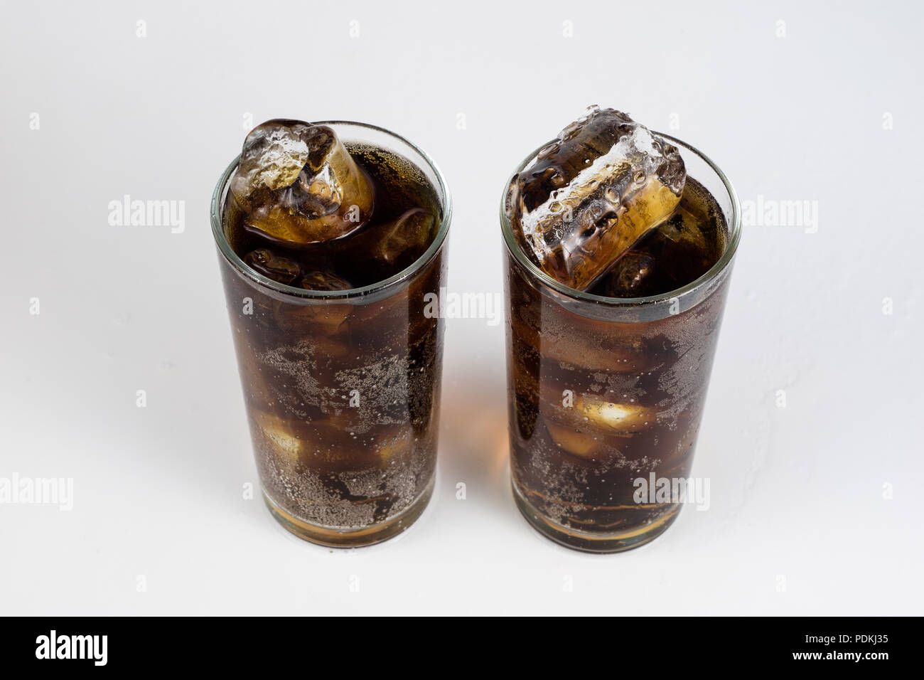 Cold drink with ice in a glass on a white table. A way to cool down on ...
