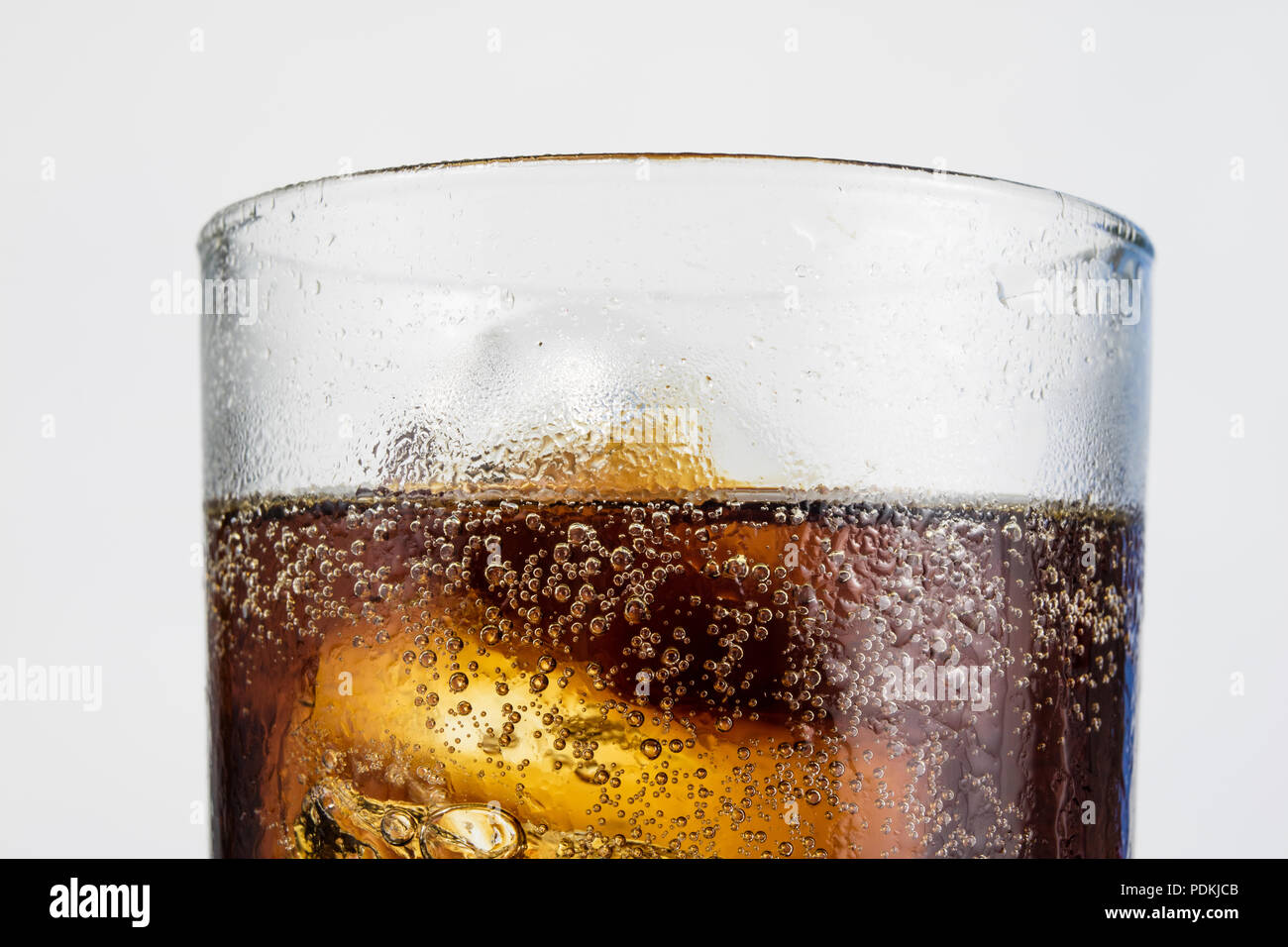 Cold drink with ice in a glass on a white table. A way to cool down on ...