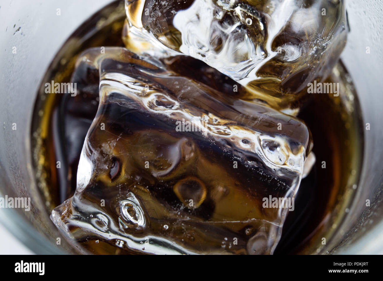 Cold drink with ice in a glass on a white table. A way to cool down on ...