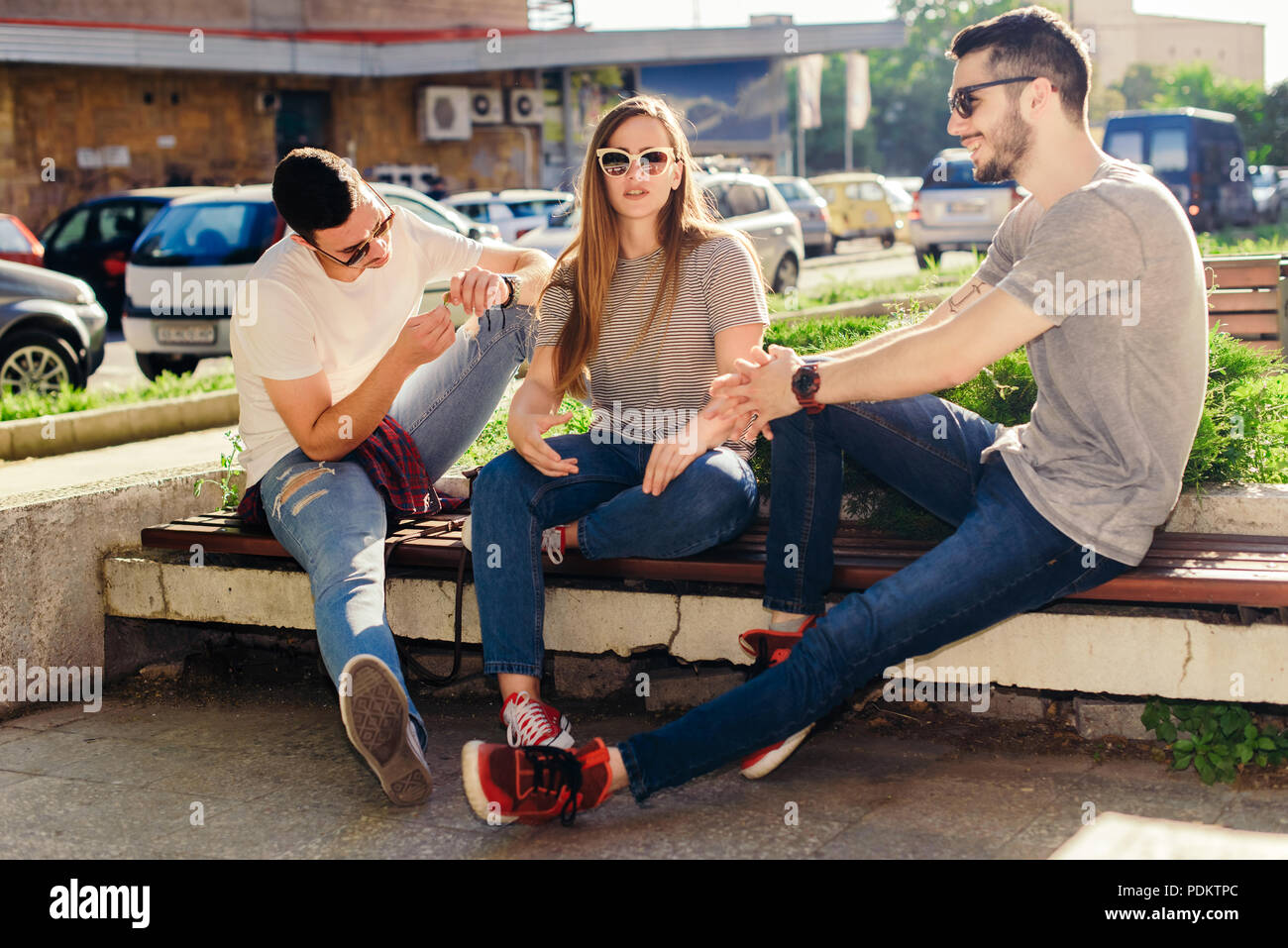 Group of friends having fun together while sitting on bench in summer ...