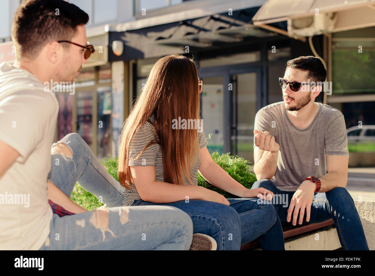 Positive three friends is talking while siiting on the bench Stock ...