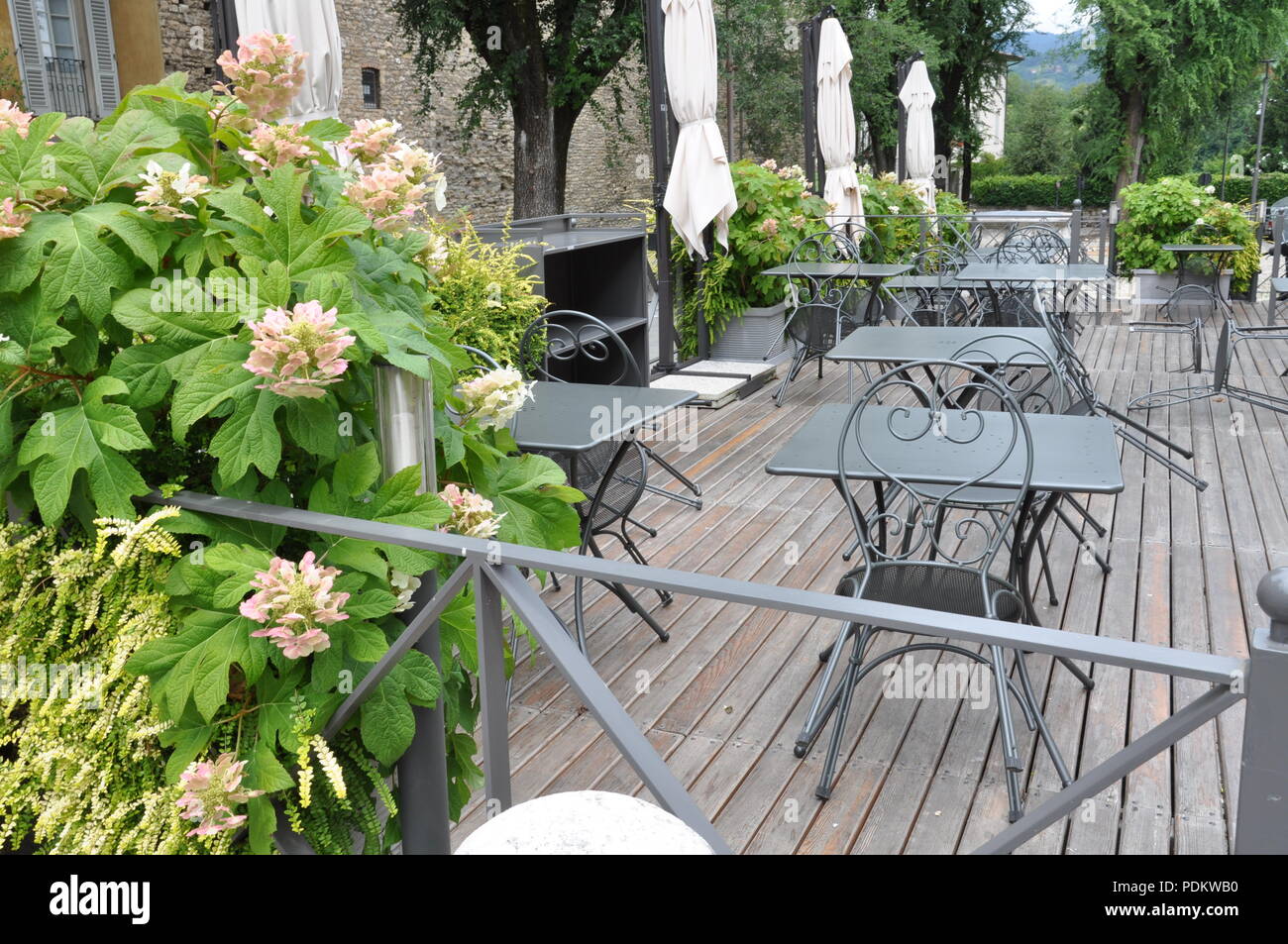 Open-air cafe in the garden with empty iron furniture on wooden terrace ...