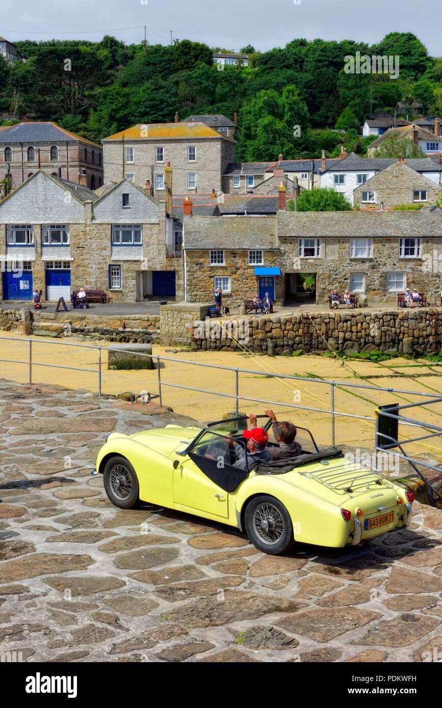 Yellow Triumph TR3 leaving harbour car park in,Mousehole,Cornwall ...