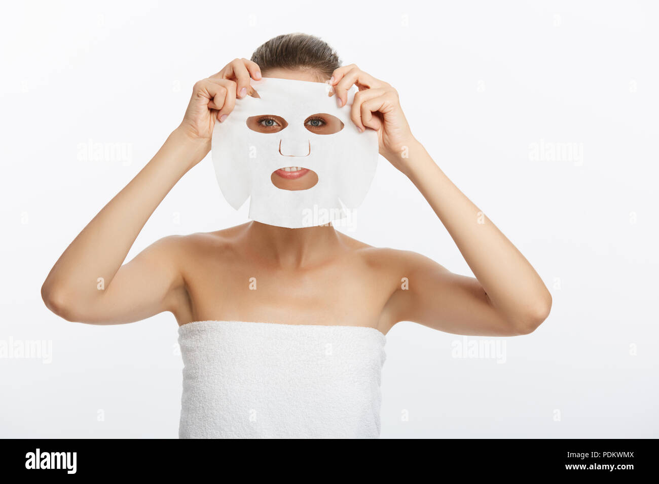 Young girl with facial mask looking at camera over white background ...