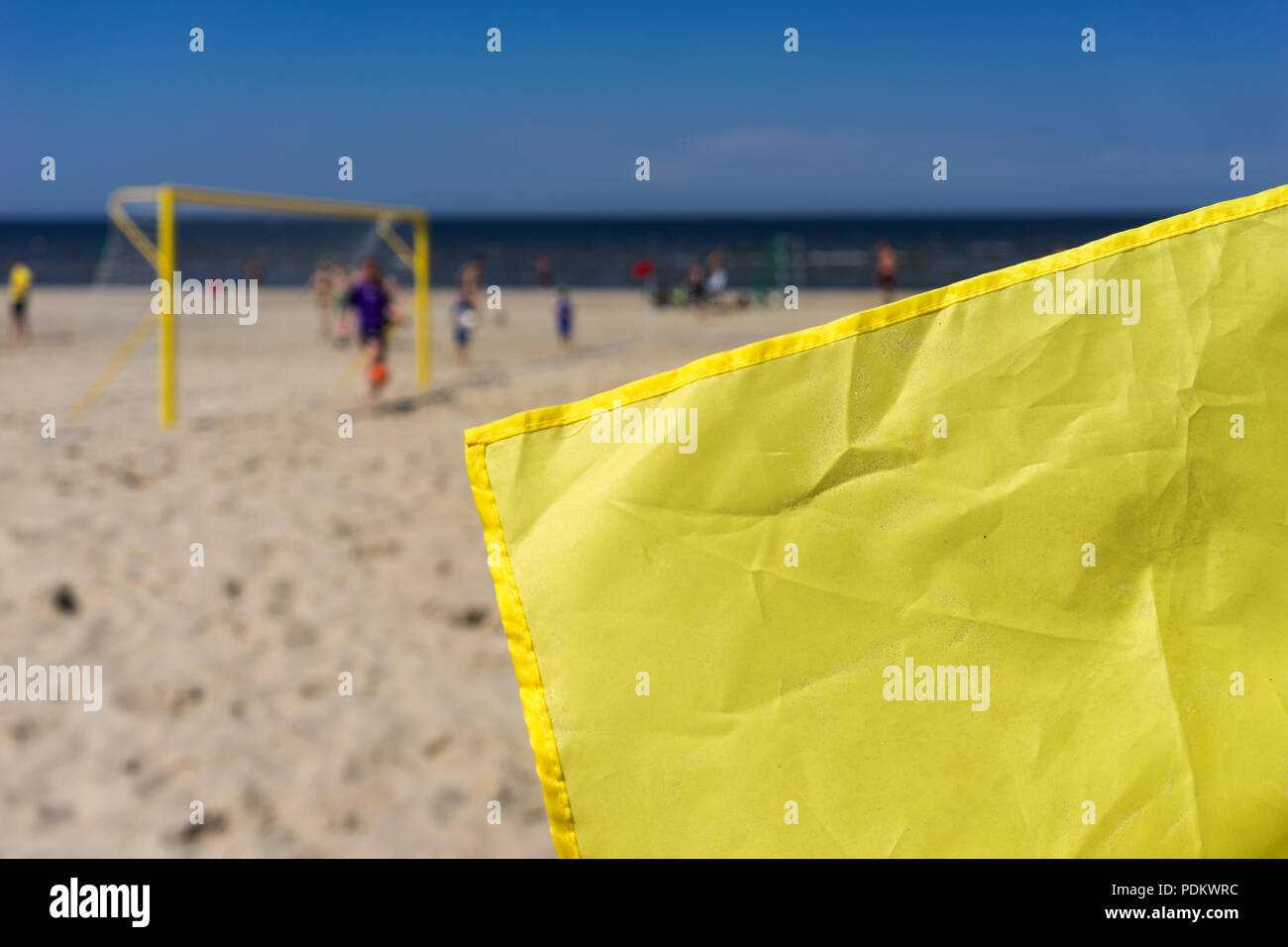 Yellow flag with sand on the football field by the sea on the beach ...
