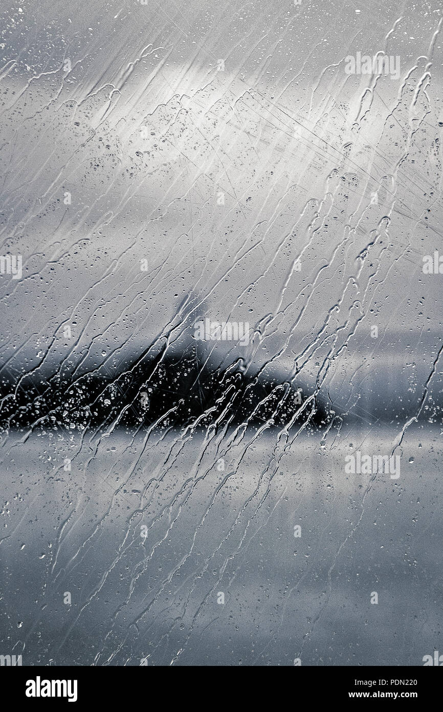 Rain leaves wet traces on the window. View of a bridge over a fjord in ...