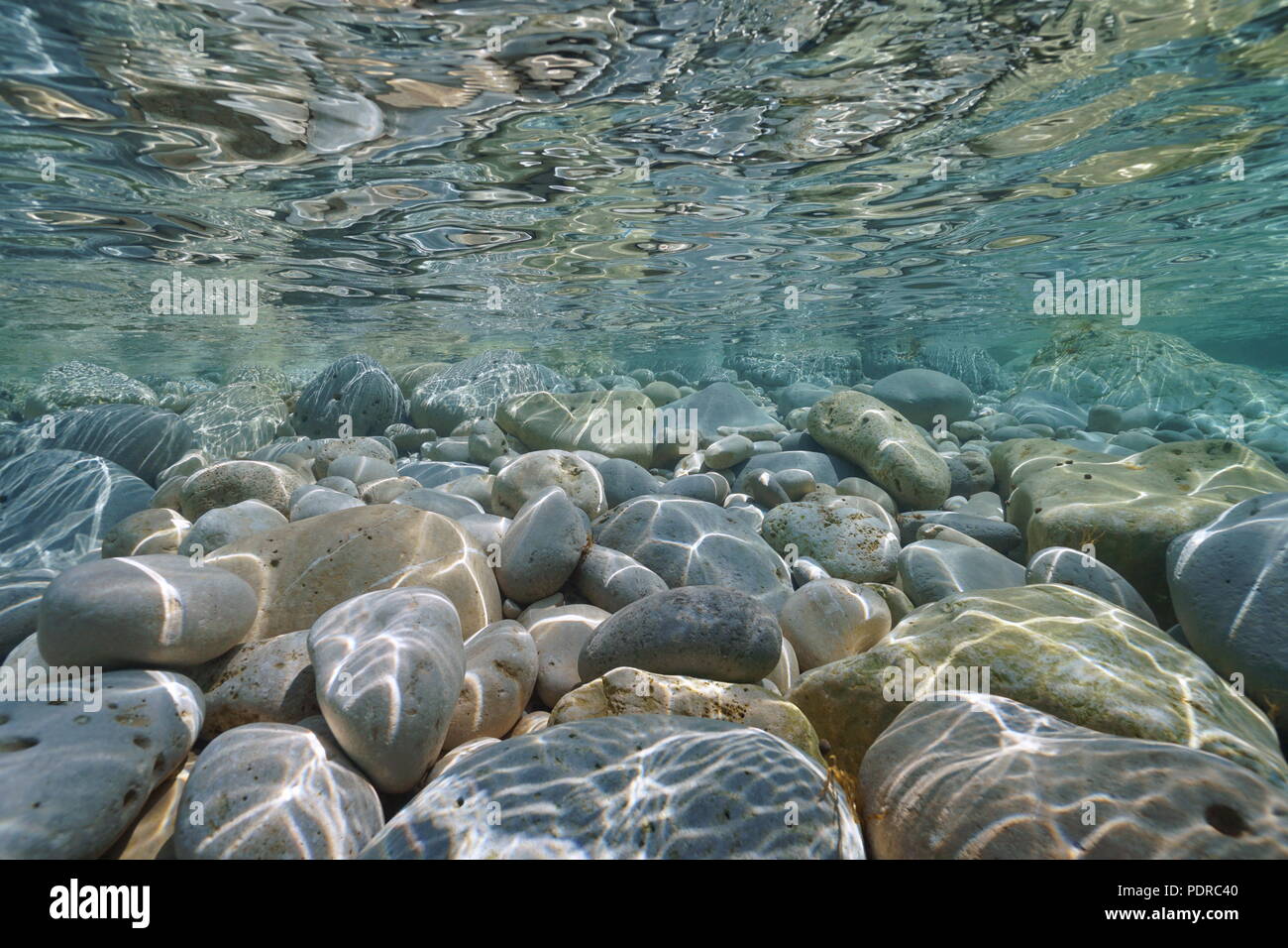 Underwater pebbles and rocks below water surface on the seashore ...
