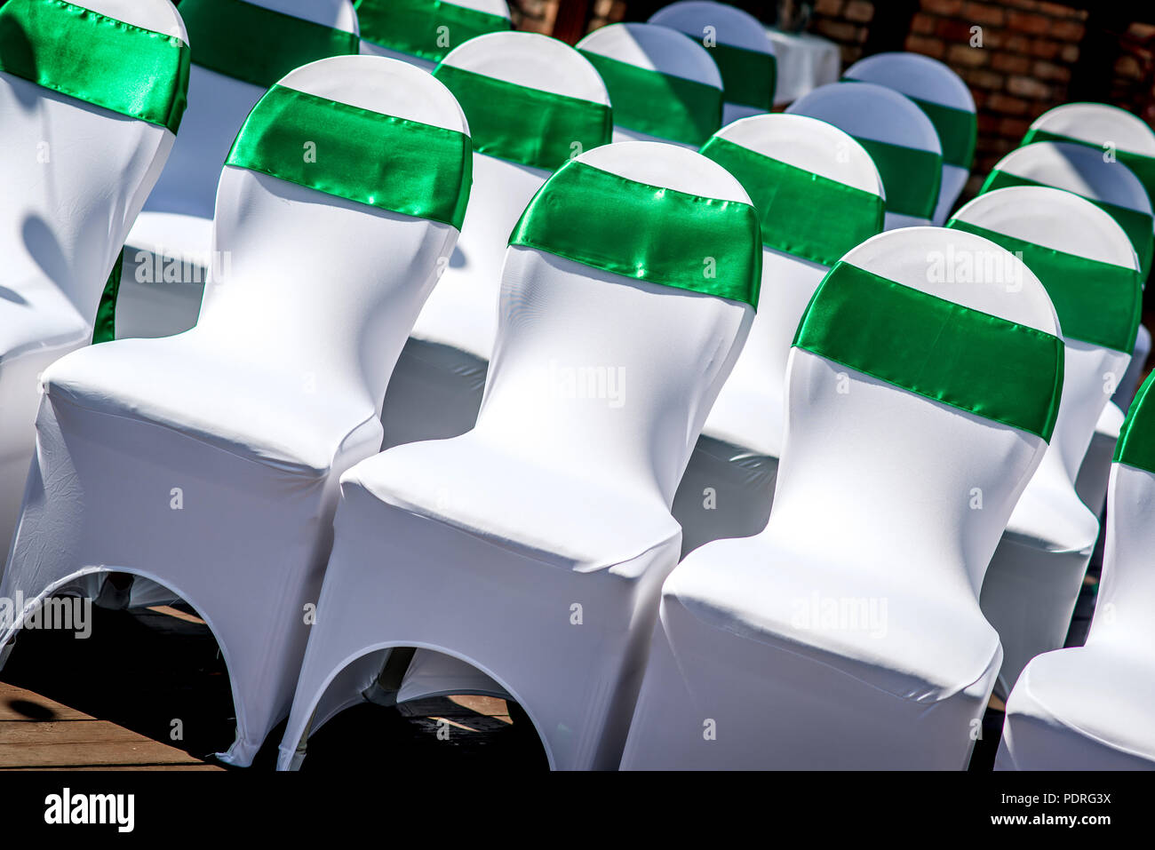 White wedding chairs with green ribbon outdoors Stock Photo - Alamy