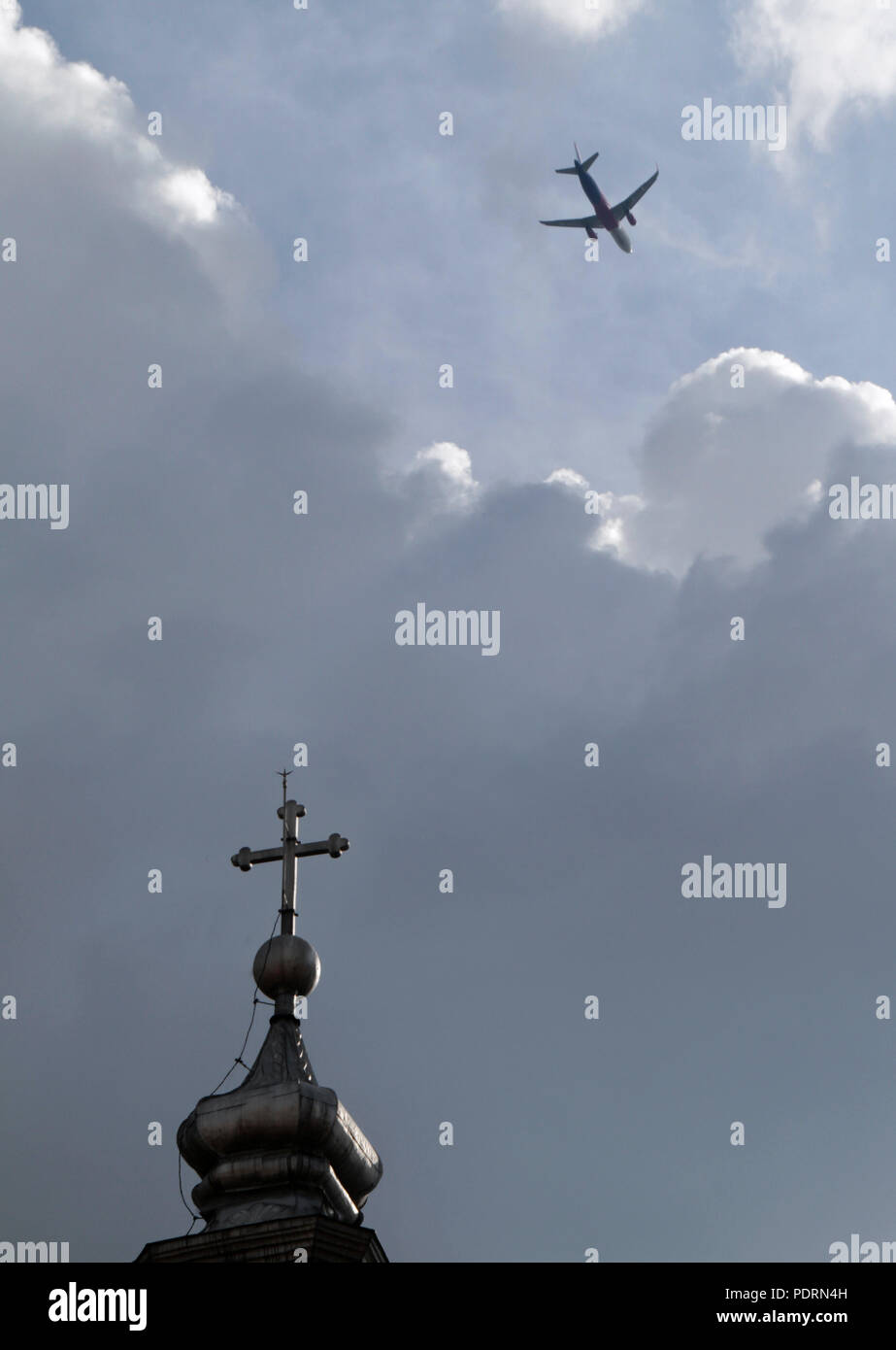 Plane flying above church in the cloudy skies Stock Photo - Alamy