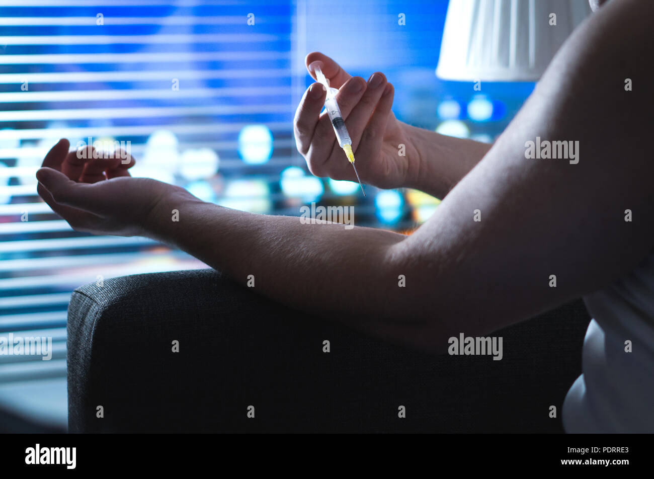 Heroin addict using drugs with injection needle and syringe in dark ...