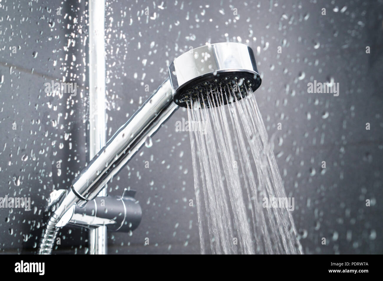 Fresh shower behind wet glass window with water drops splashing. Water ...