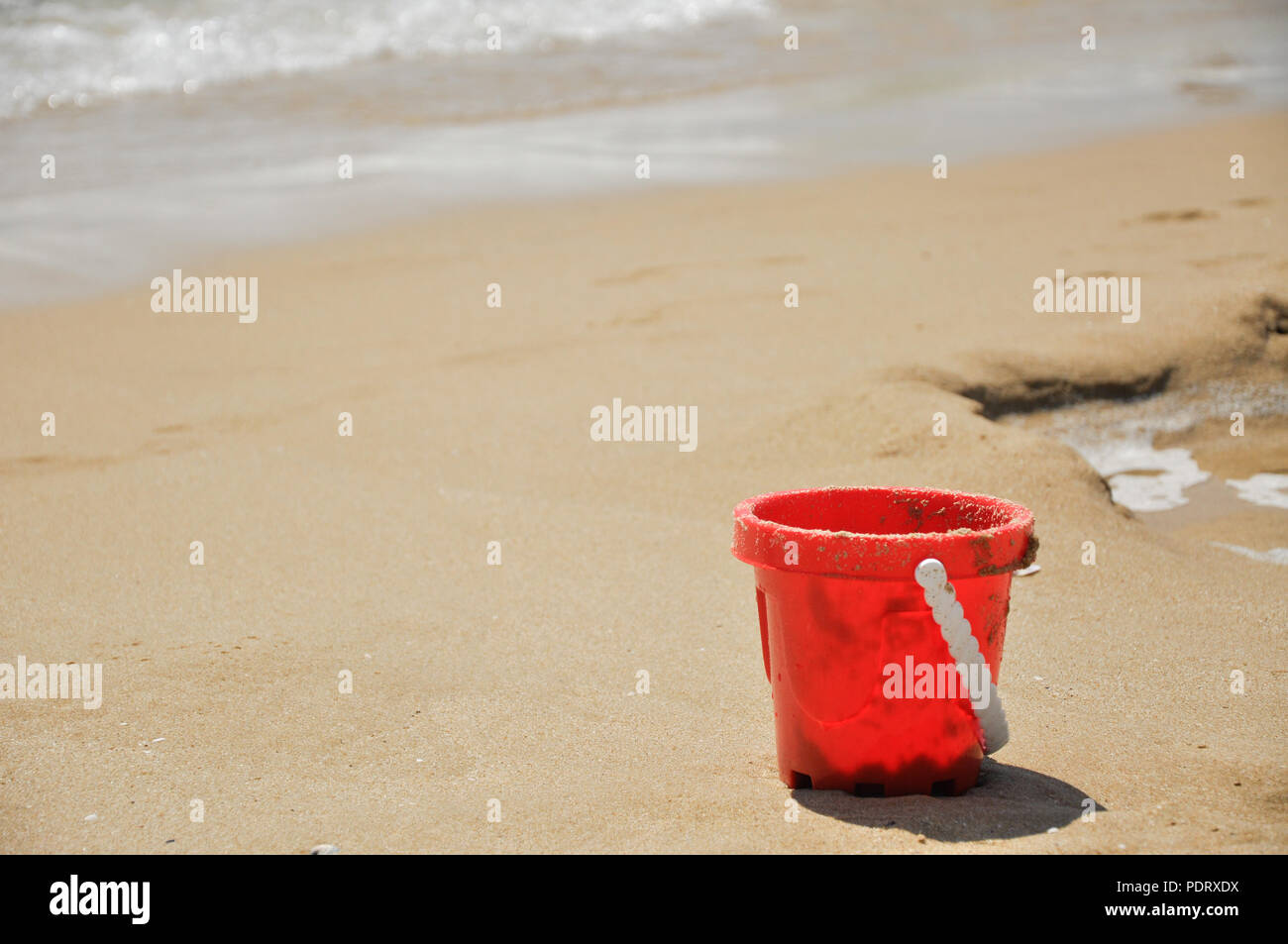 Red bucket on a beach Stock Photo - Alamy