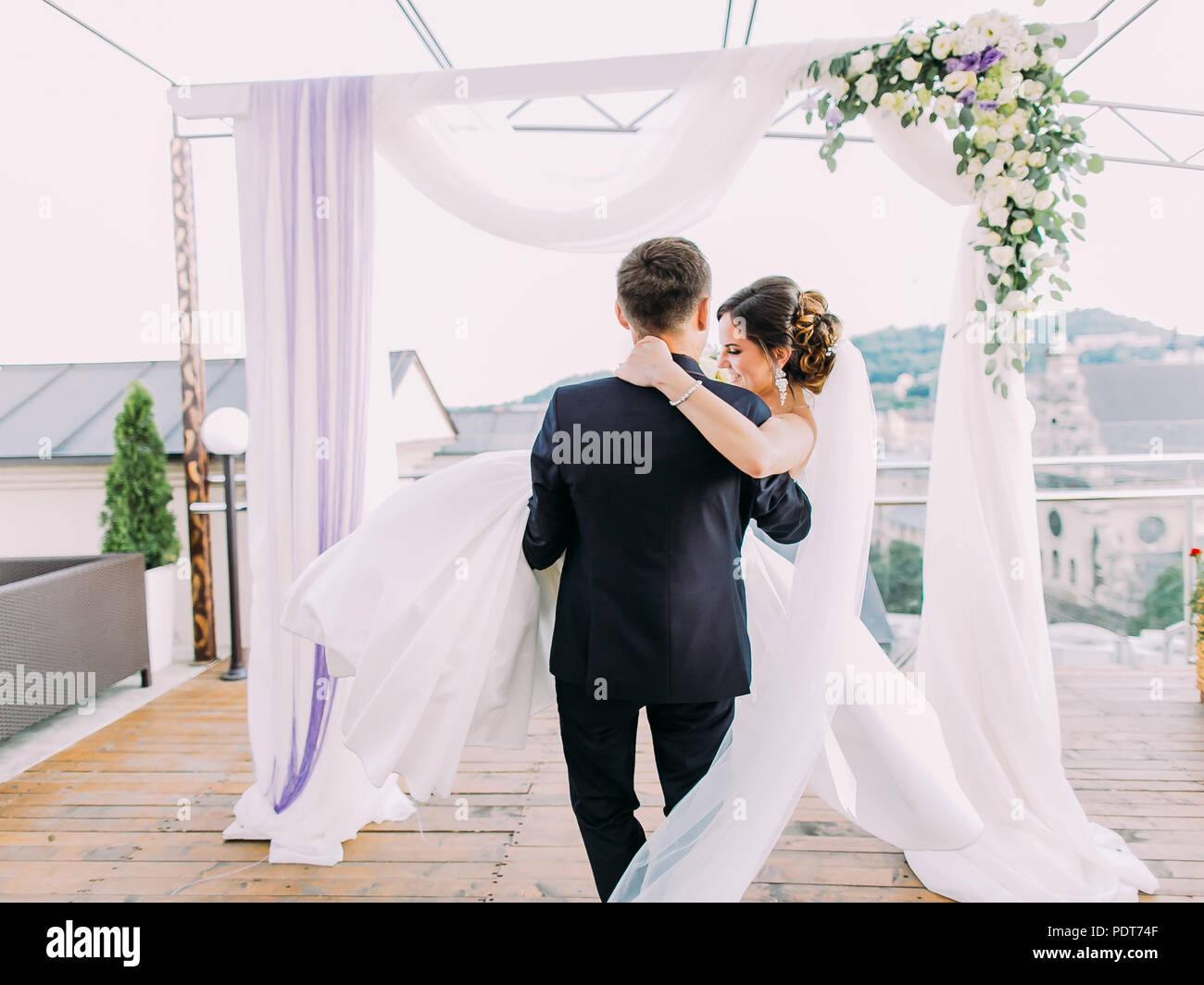 The back view of the groom carrying the bride to the wedding arch Stock ...