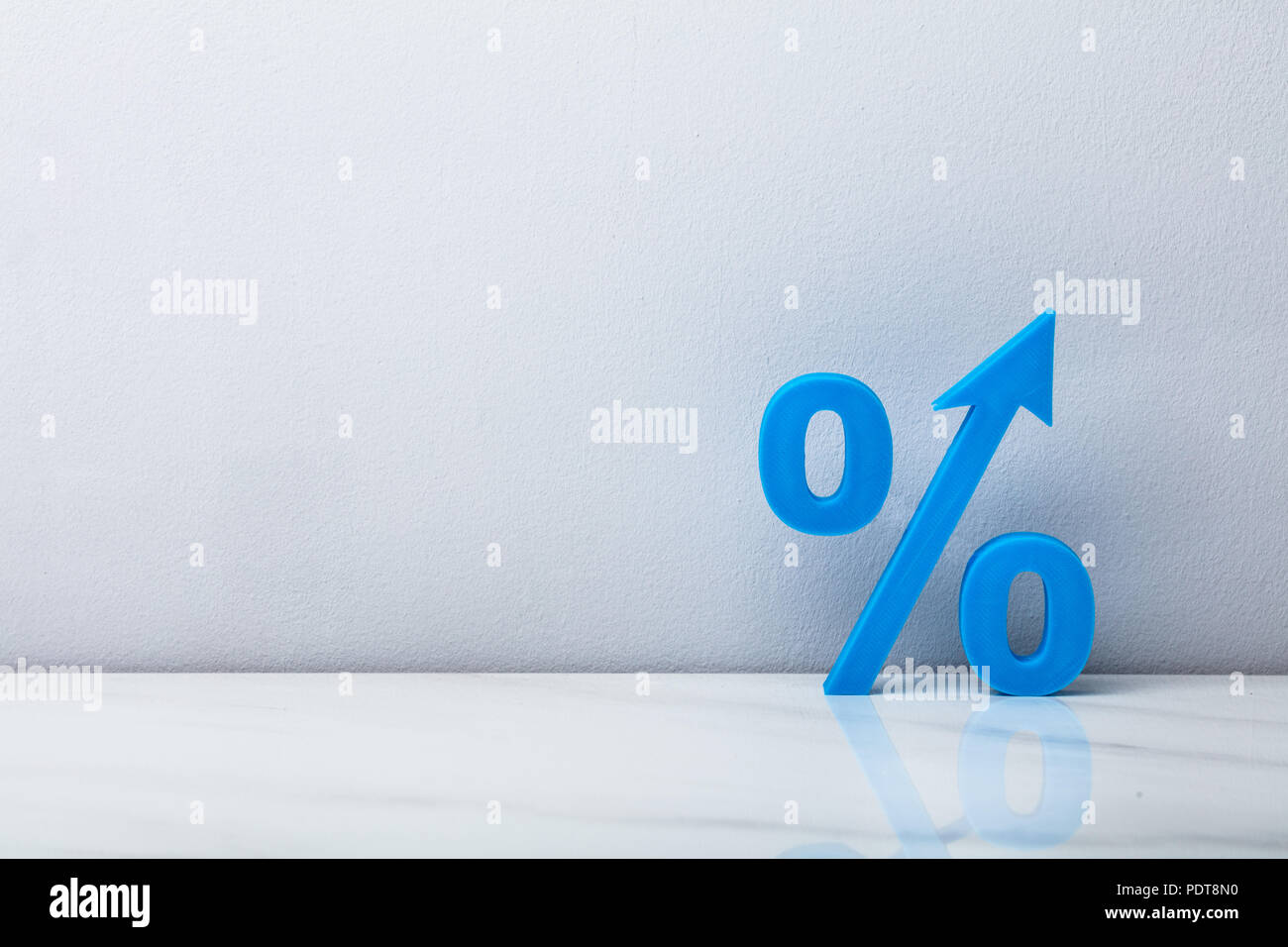 Blue Percentage Sign With Arrow In Front Of Wall Stock Photo - Alamy