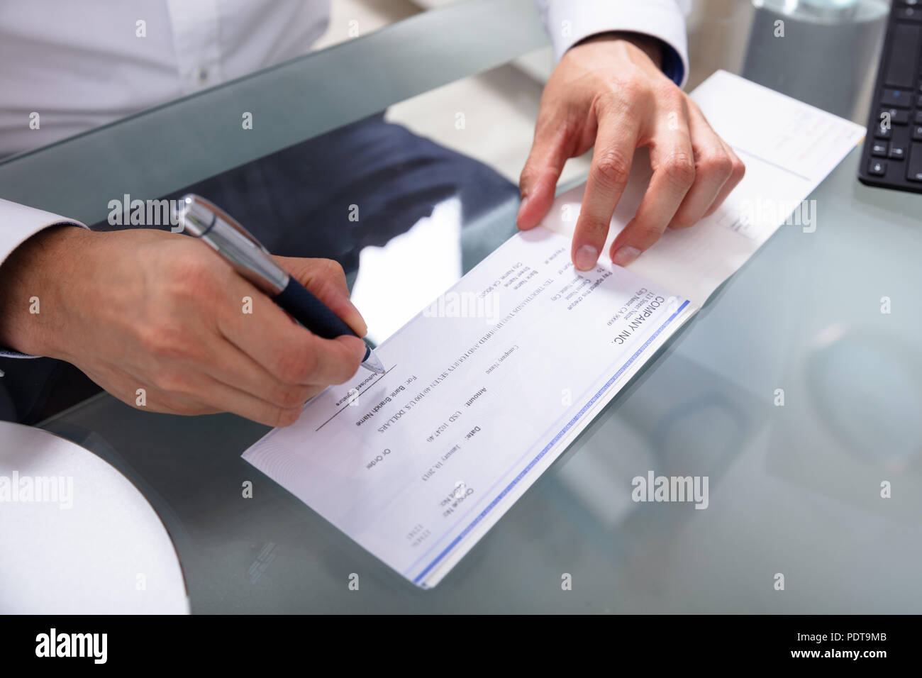 Businessman's Hand Signing Cheque On Glass Desk Stock Photo - Alamy