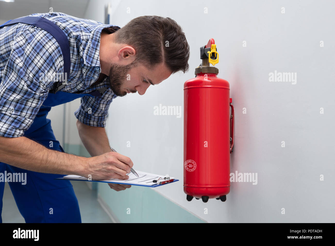Young Male Technician Checking Symbol On Fire Extinguisher Stock Photo ...