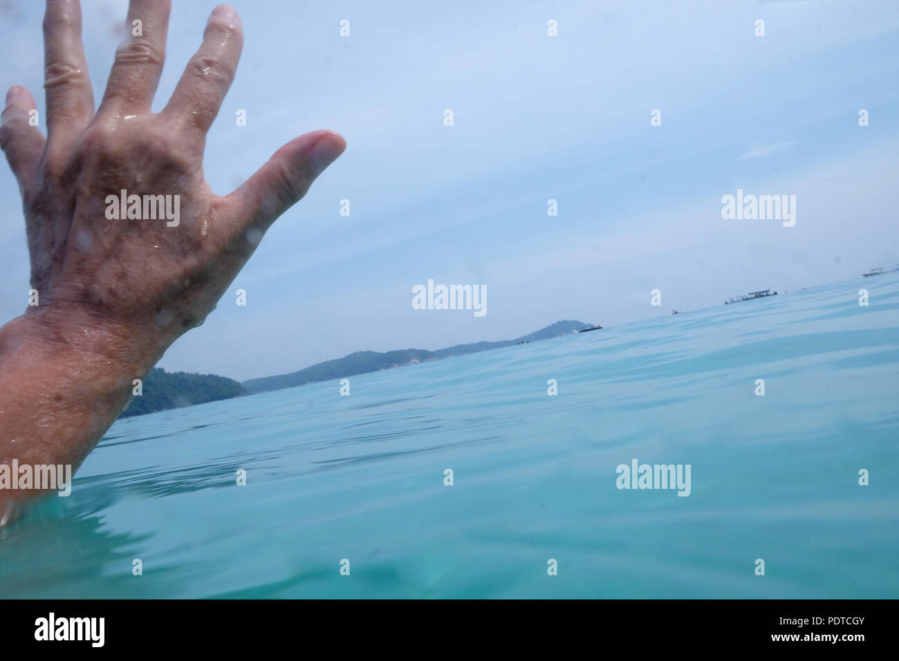 A fifty year old woman’s hand half underwater in the sea and the ...