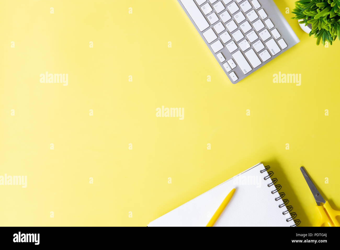 Above Office desk with computer keyboard, notebook paper, pen and plant ...