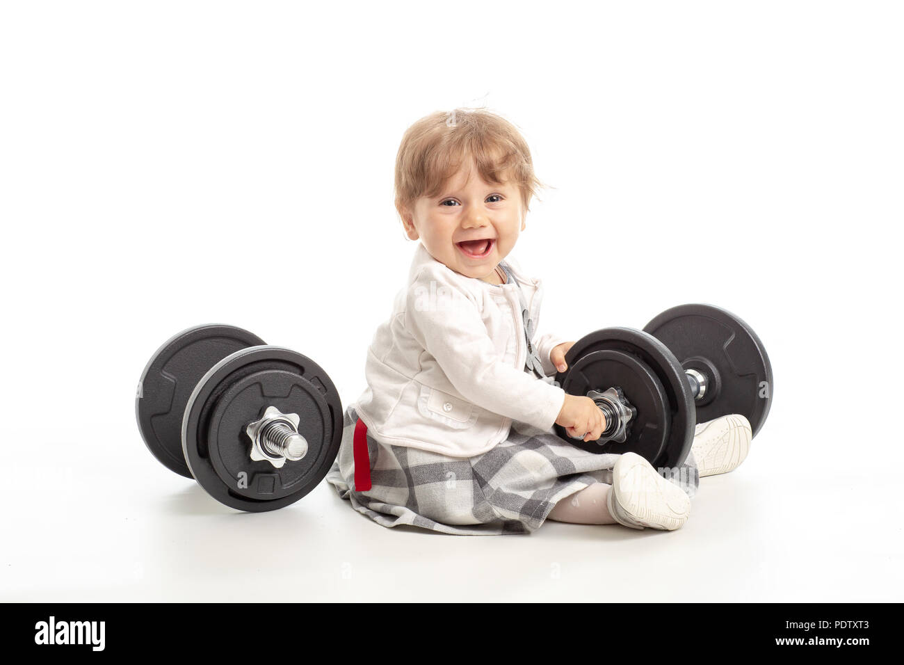 Small female baby playing with gym weights in studio shot on white ...