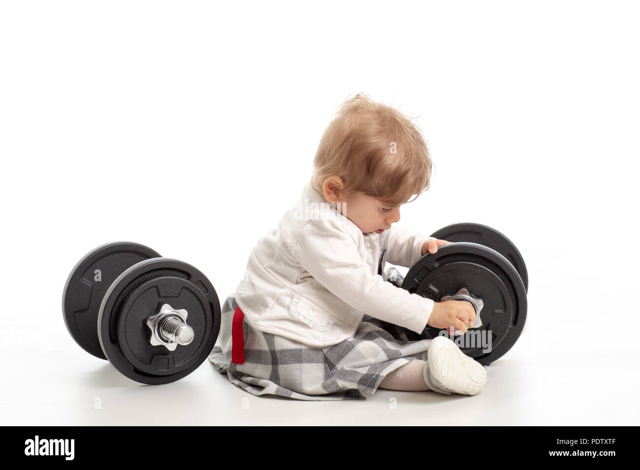 Small female baby playing with gym weights in studio shot on white ...