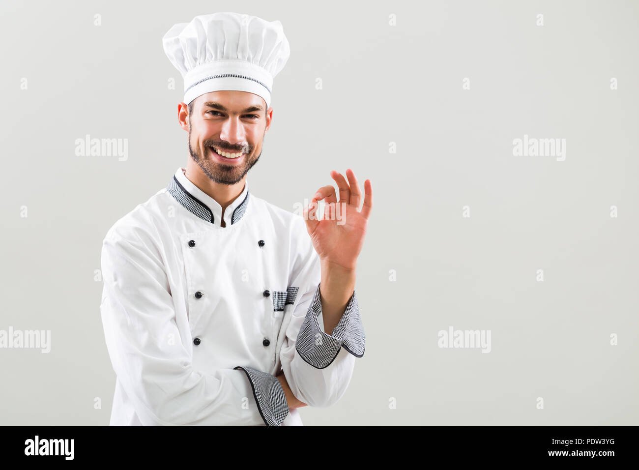 Smiling chef showing ok sign on gray background Stock Photo - Alamy