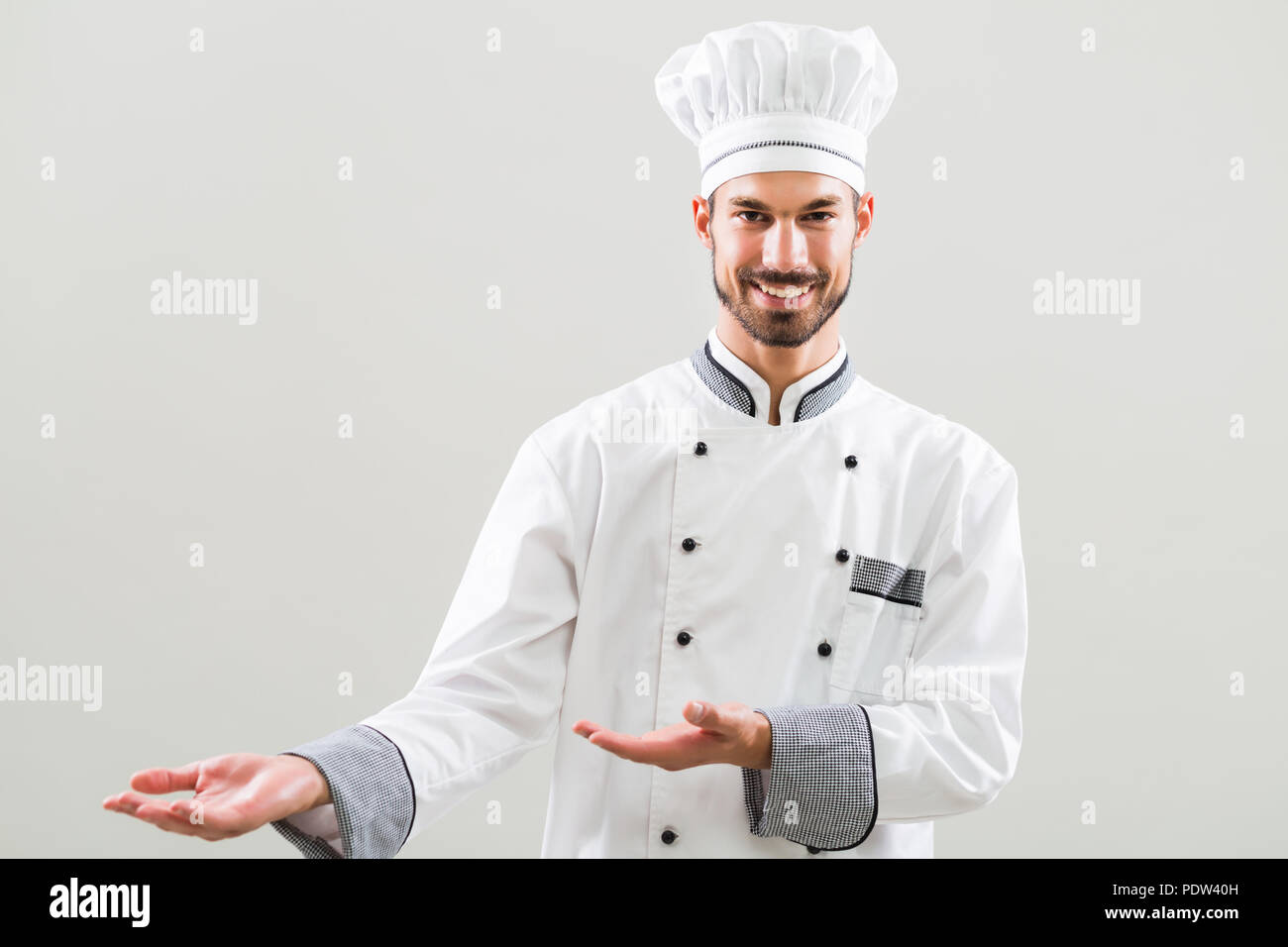 Smiling chef showing welcome gesture on gray background Stock Photo - Alamy