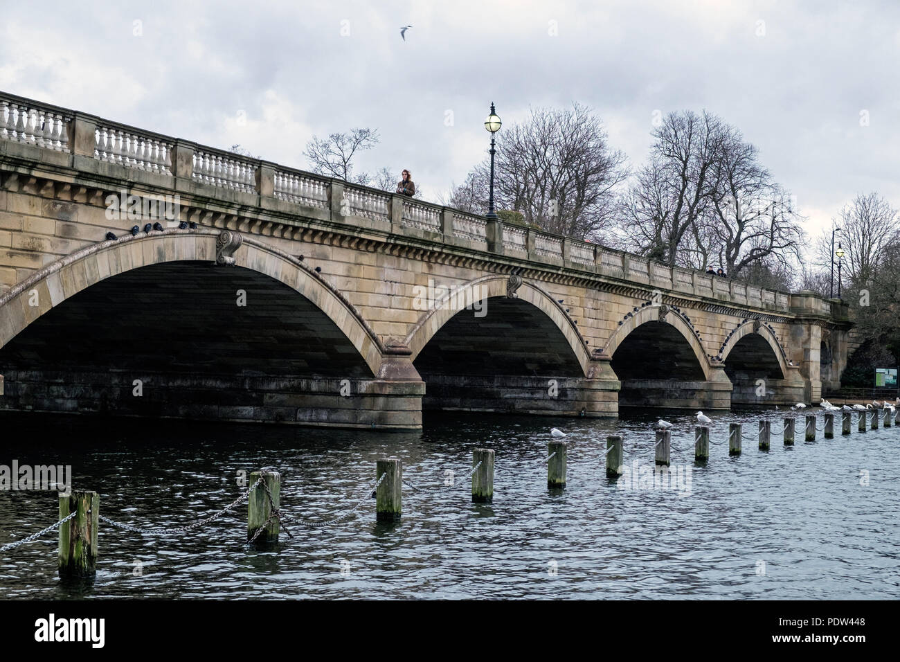 A lady walks across the Serpentine Bridge on the border of Hyde Park ...