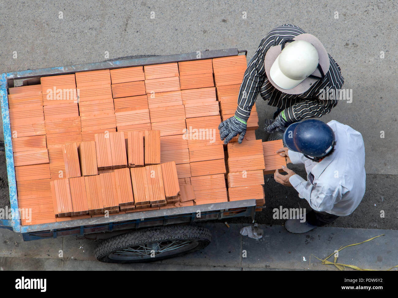 Worker carries bricks from a cart on bicycle. Construction work on the ...