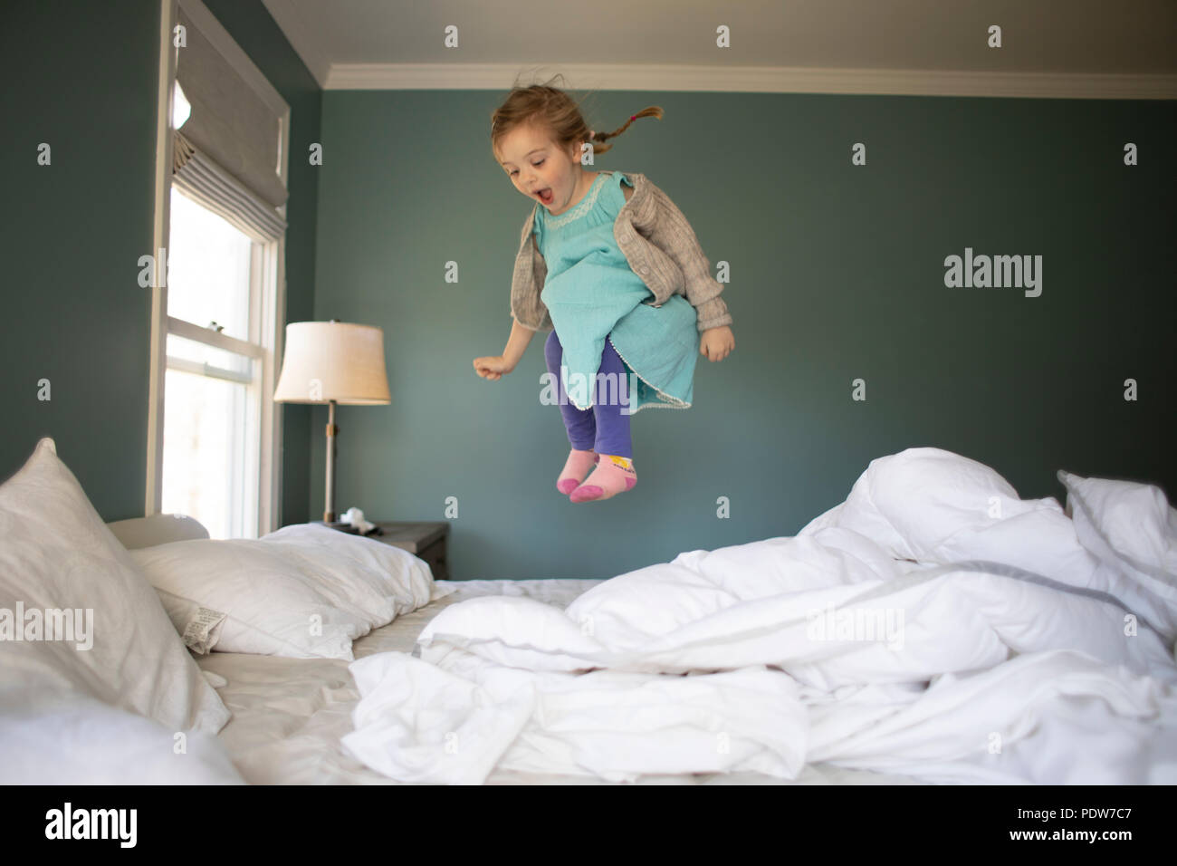 Child jumping on a bed Stock Photo - Alamy