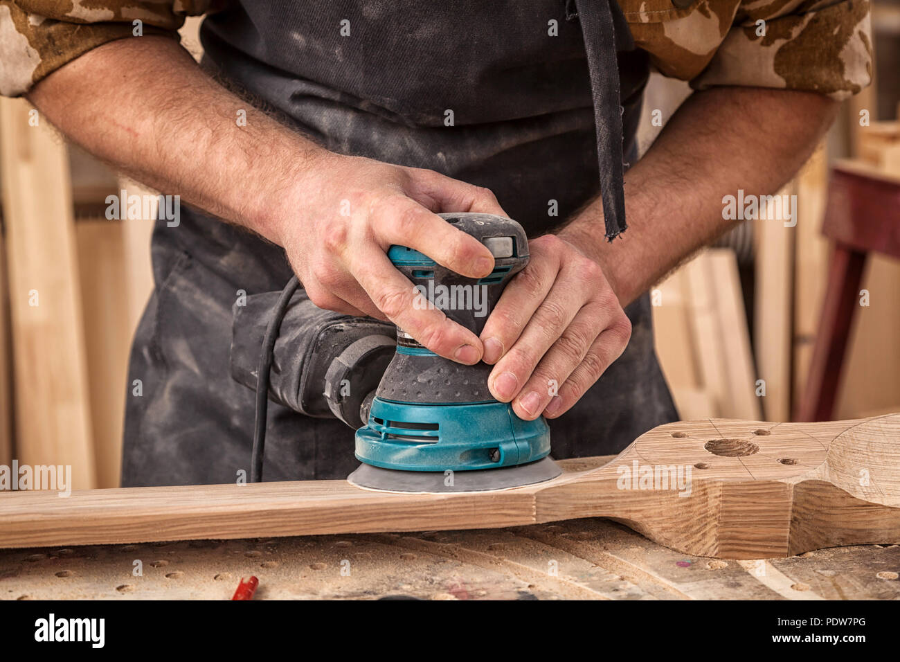 Close up of an young man builder carpenter equals polishes wooden board ...
