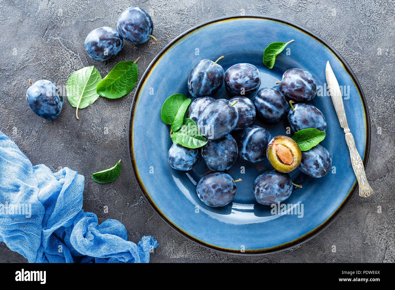 Fresh juicy sweet plums on plate with leaves Stock Photo - Alamy