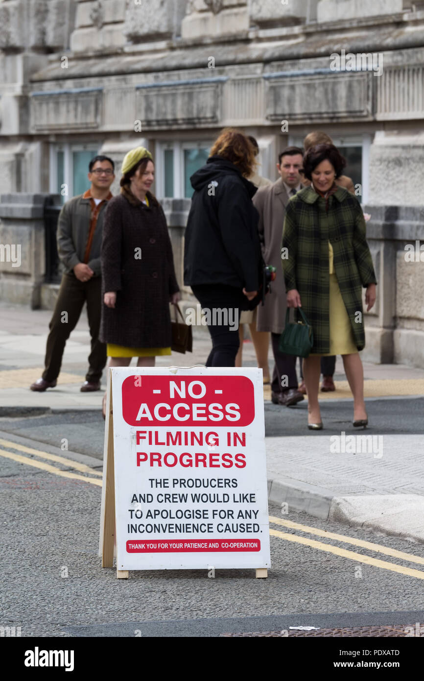 Film extras dressed in 1960s style clothing awaiting instruction before ...