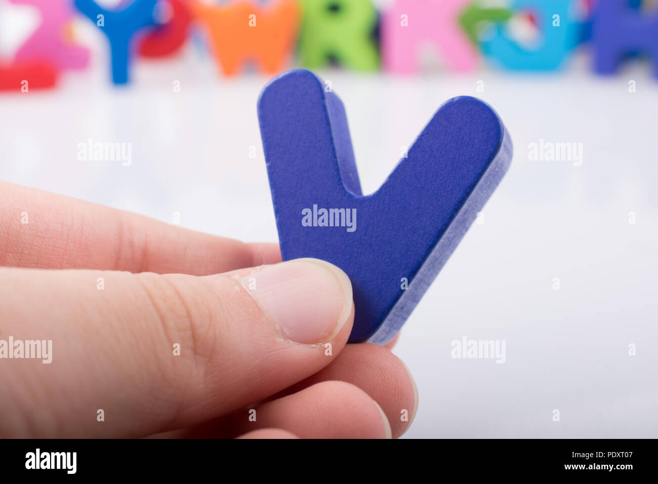 Hand holding letter cube V of made of wood Stock Photo - Alamy