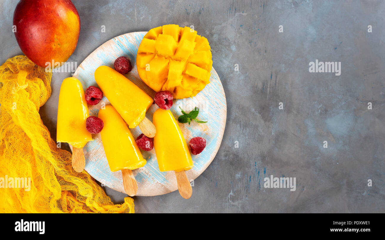 Top view of mango frozen ice in lolly pop shape with raspberry. Copy ...