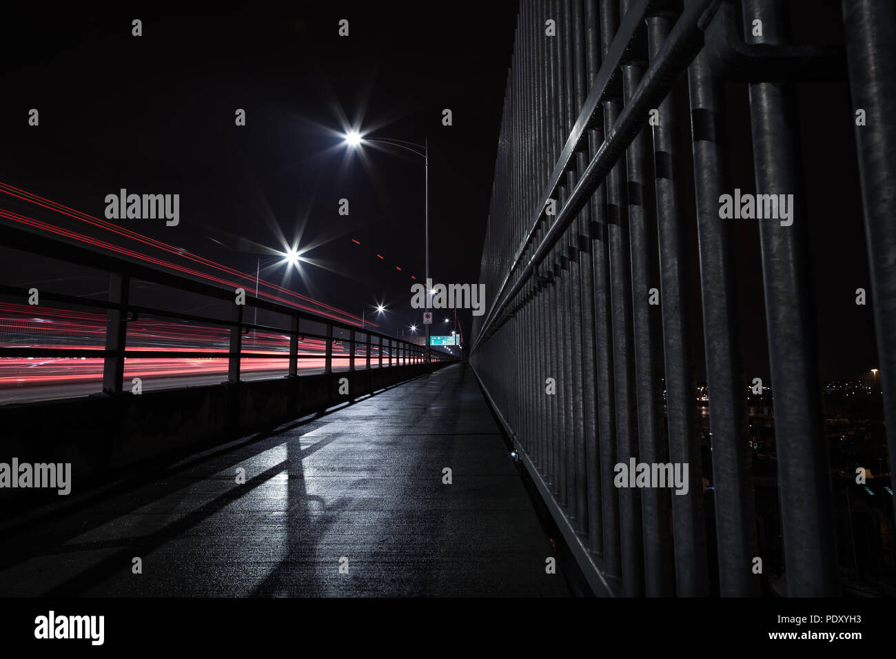 The Second Narrows Bridge sidewalk at night, with light trails from ...