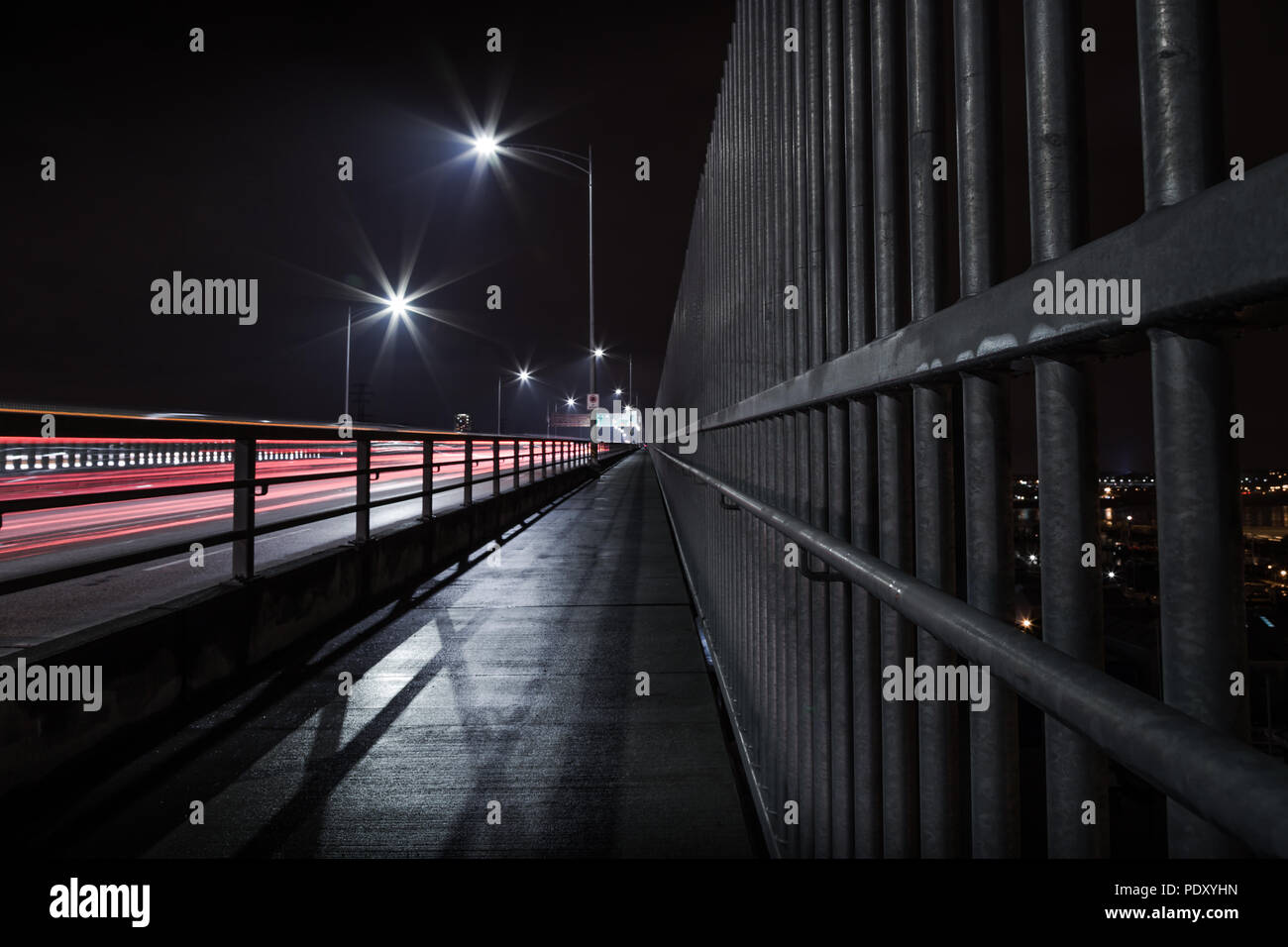 The Second Narrows Bridge sidewalk at night, with light trails from ...