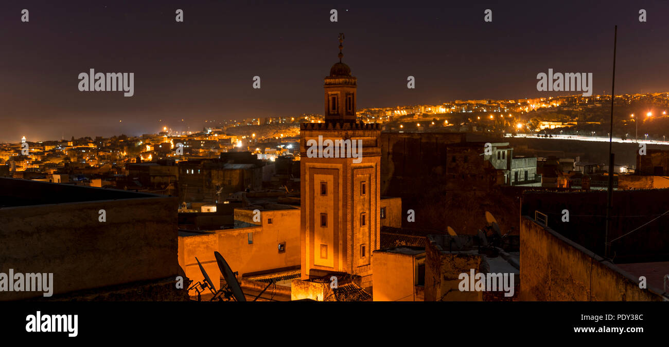 View of the illuminated old town at night, mosque with minaret, Fes ...