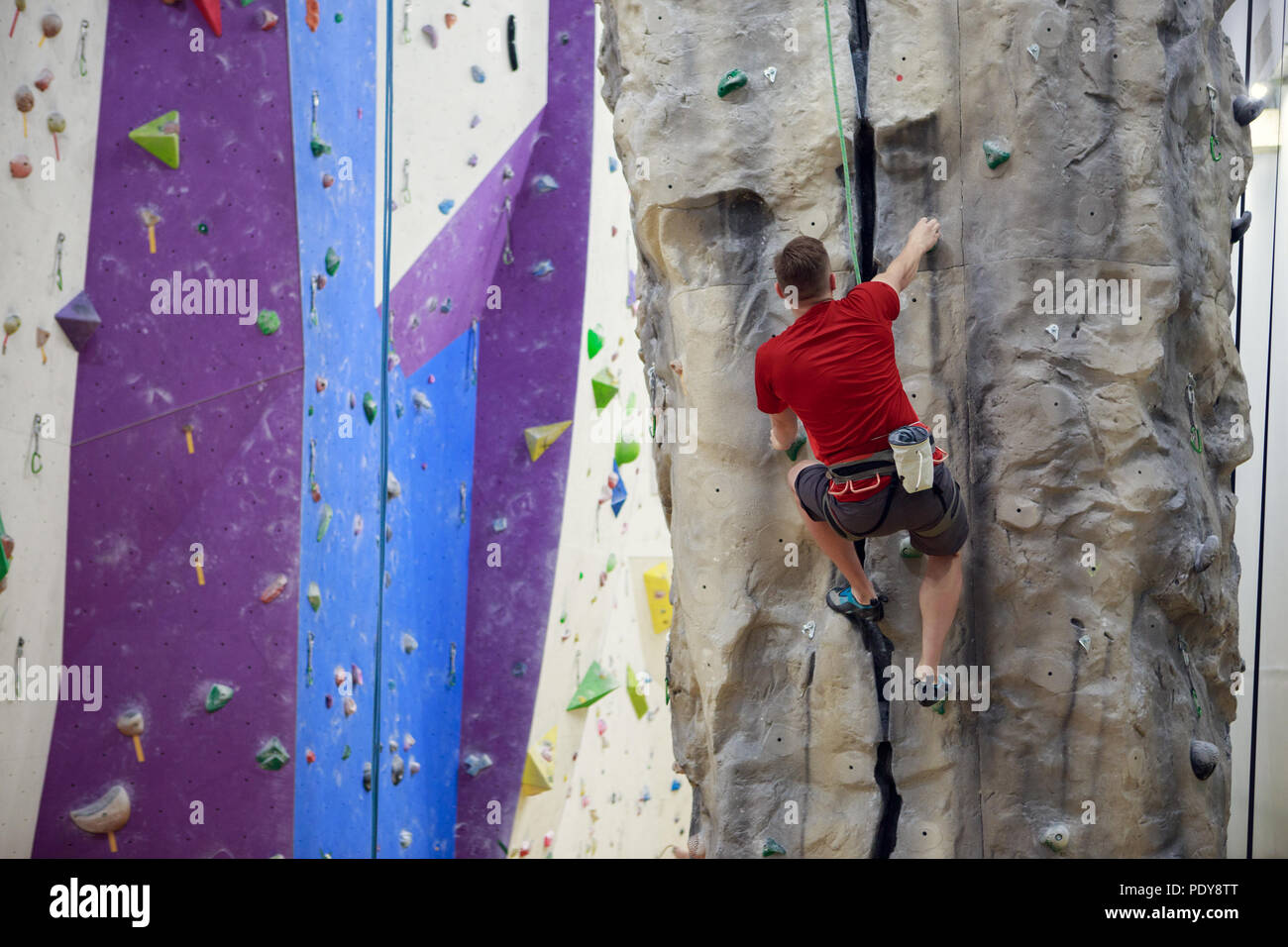 Photo from back of sportsman climbing up boulder in gym indoors Stock ...