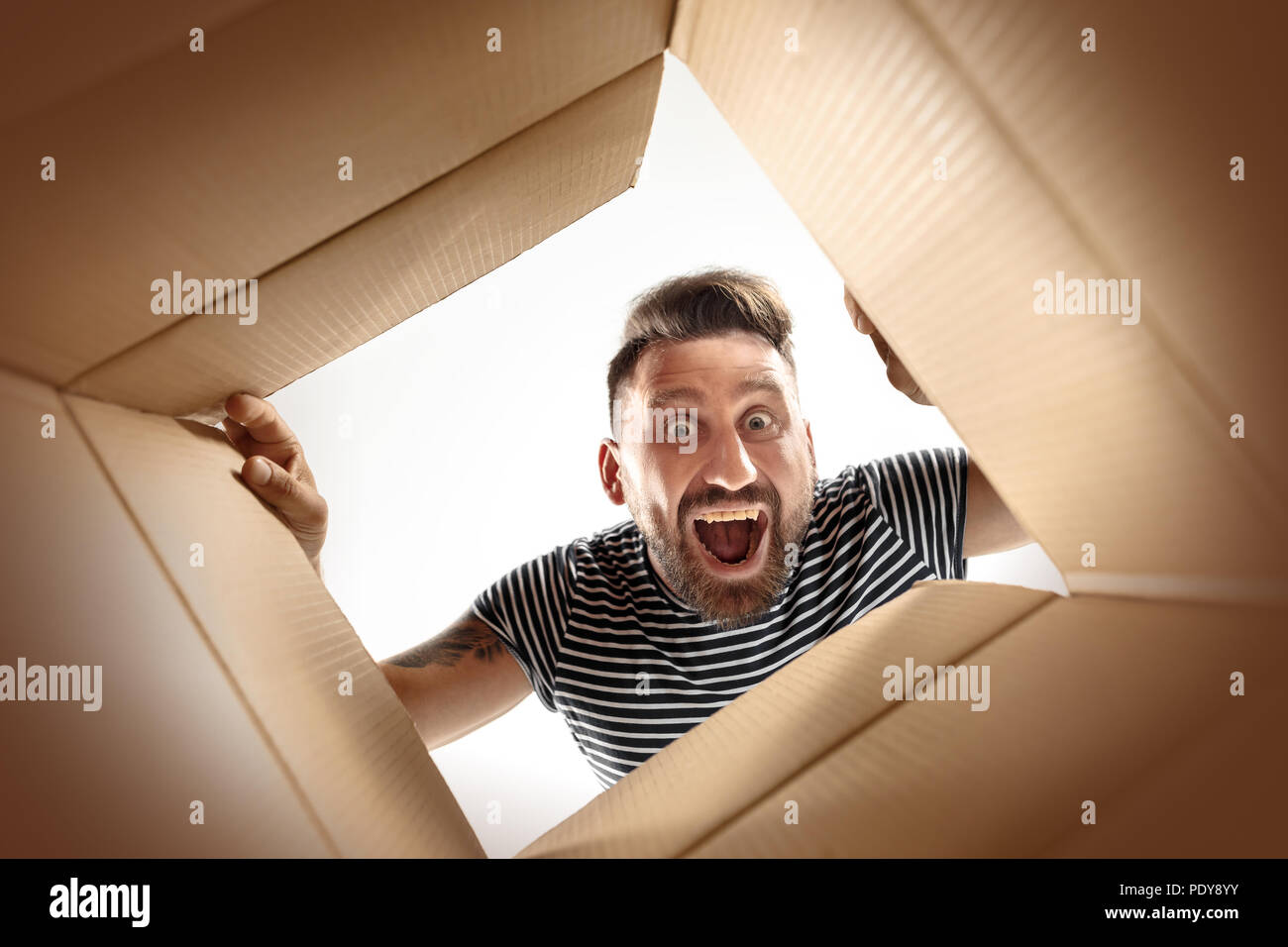The surprised man opening box and looking inside. The package, delivery ...