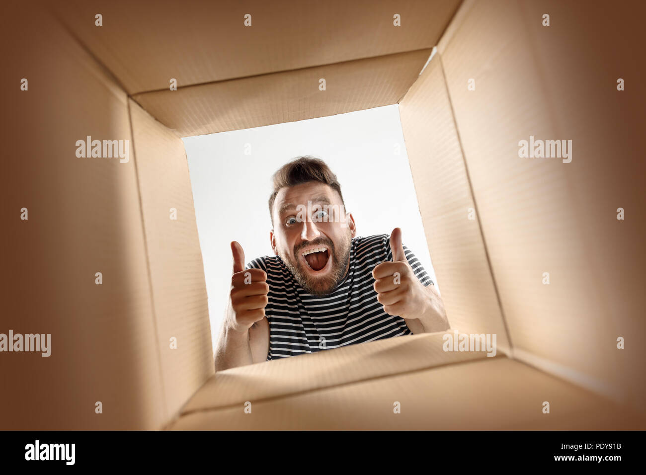 The surprised man unpacking, opening carton box and looking inside. The ...