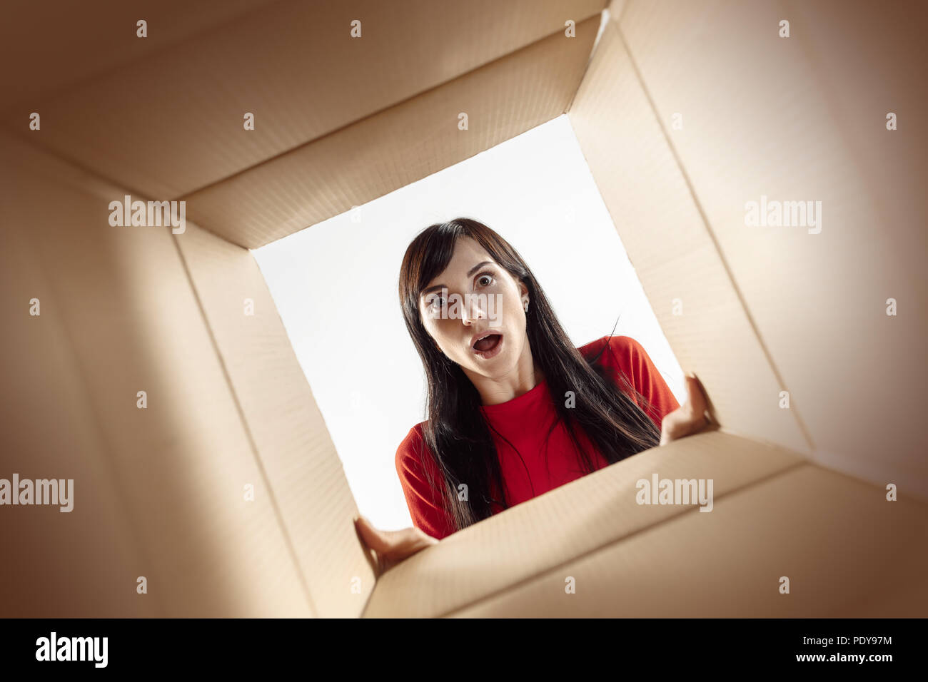 The surprised woman opening box and looking inside. The package, delivery, surprise, gift ...