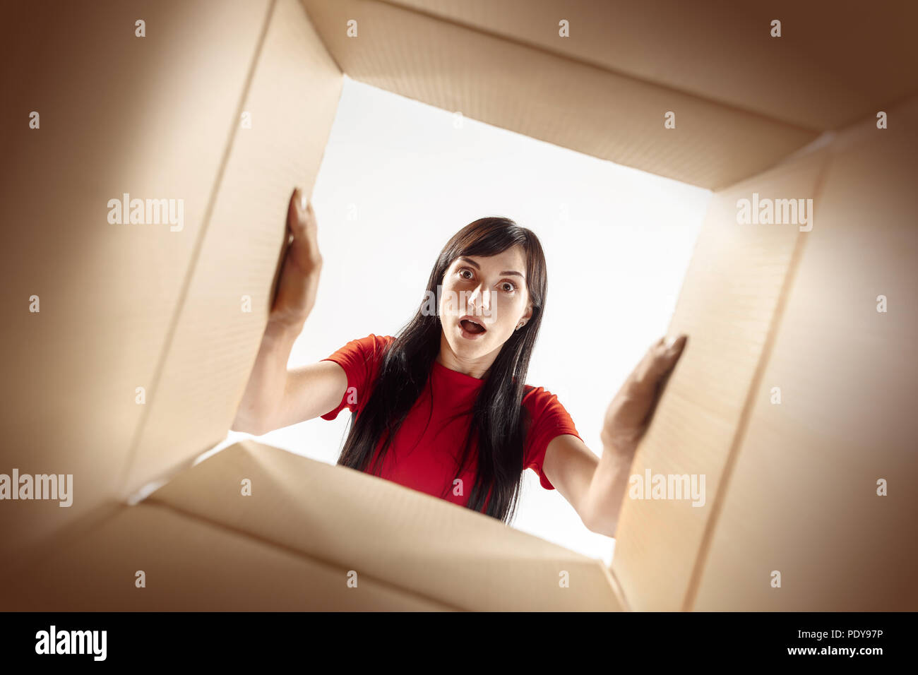 The surprised woman opening box and looking inside. The package ...