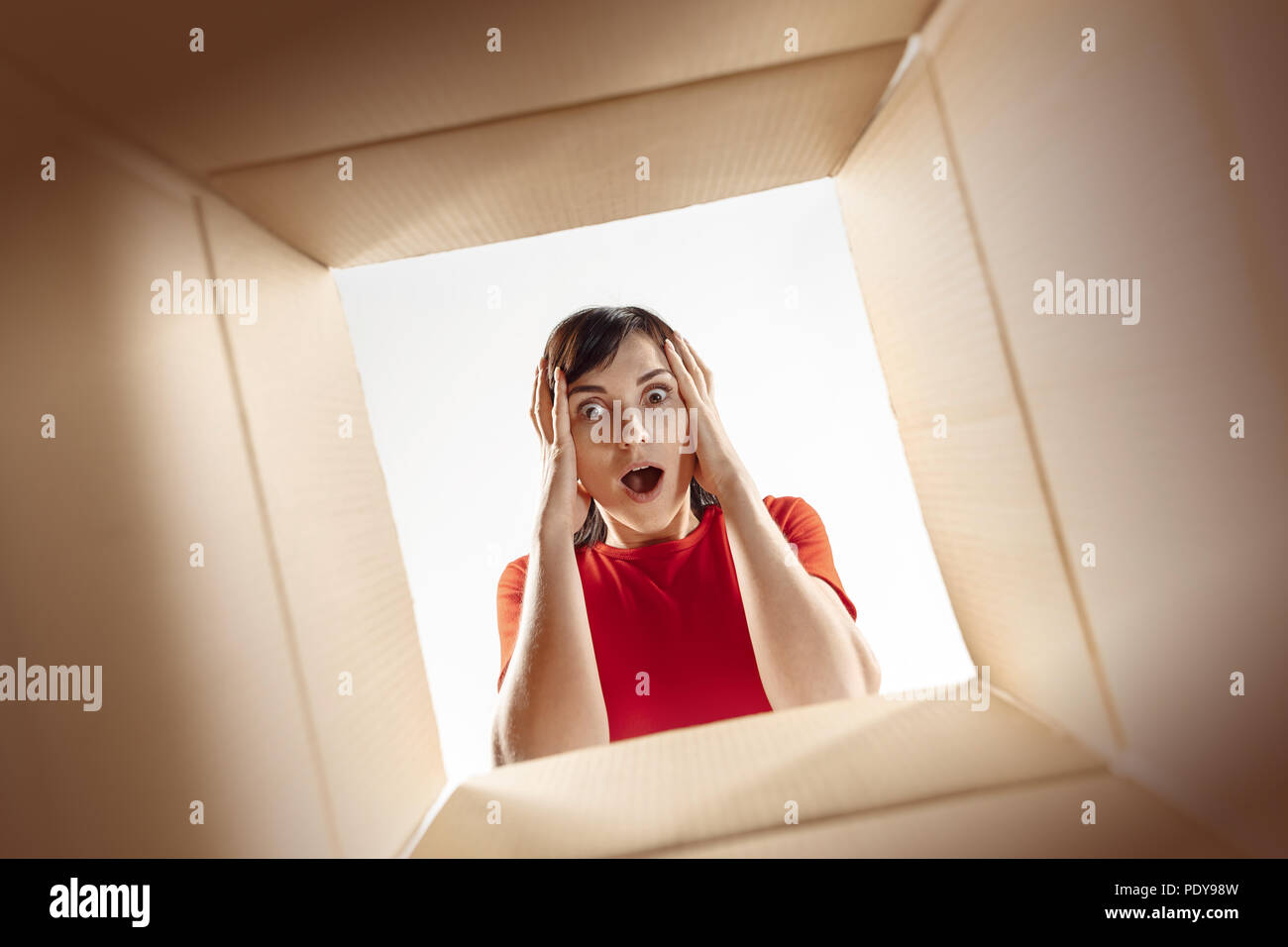 The surprised woman opening box and looking inside. The package ...