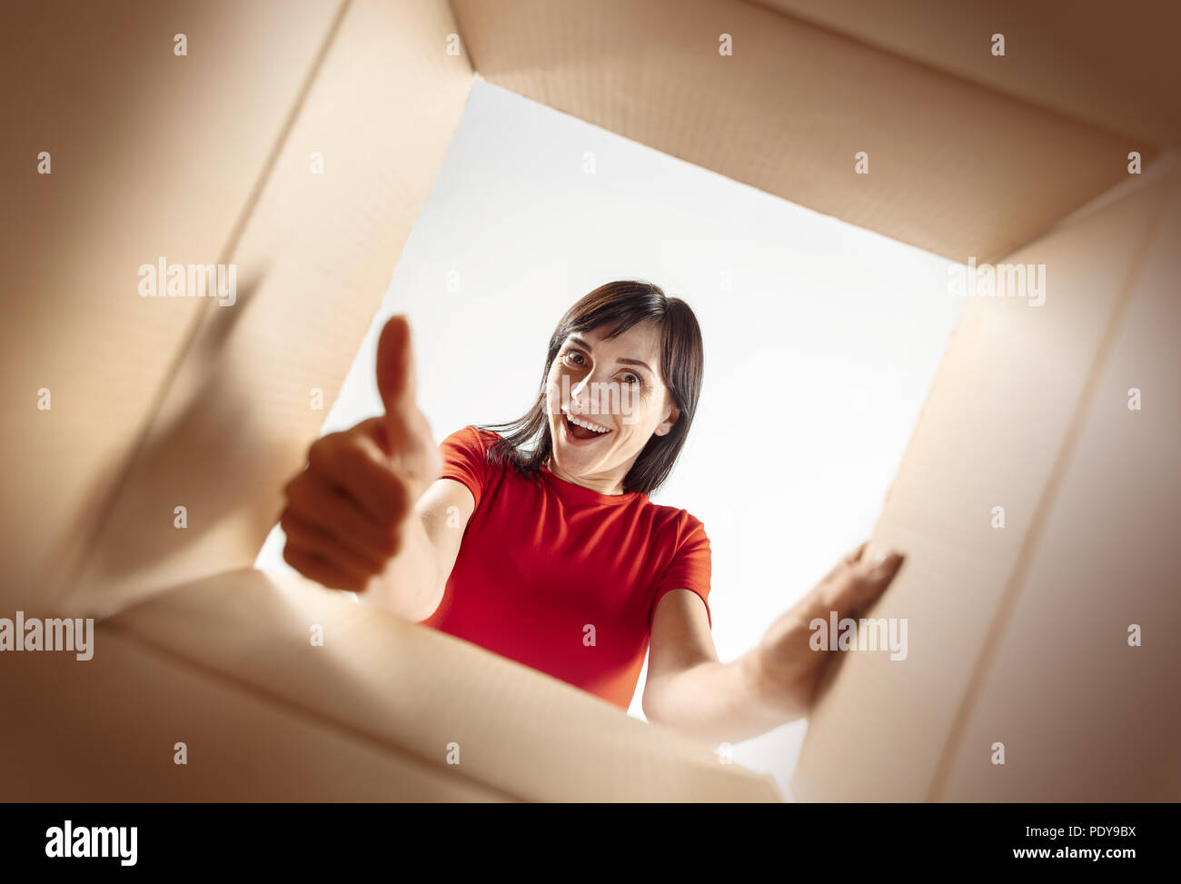 The surprised woman opening box and looking inside. The package ...