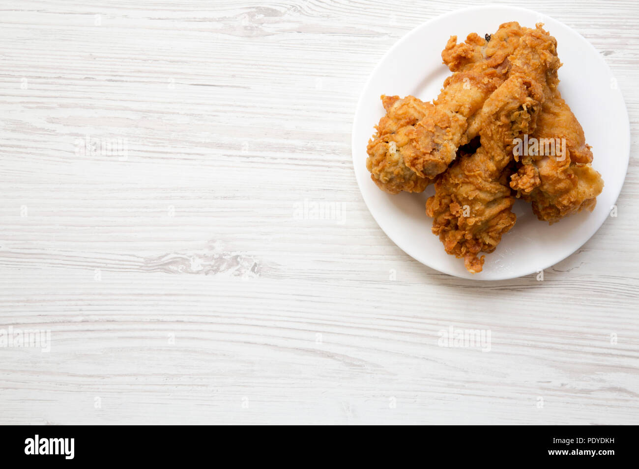 Fried chicken legs on a white round plate with copy space, overhead ...