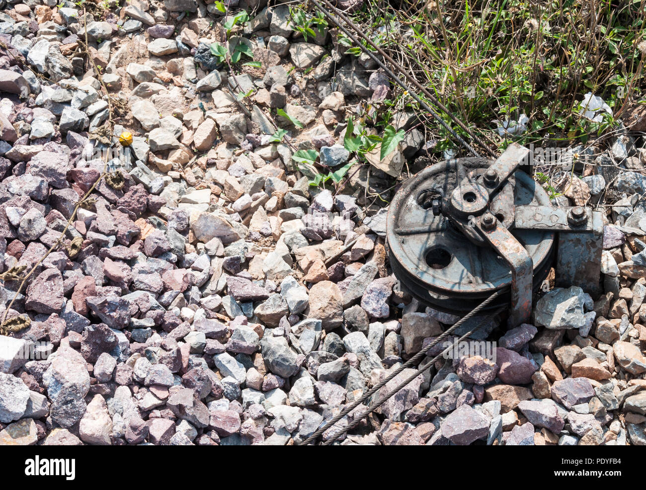Old steel pulley with the metal wire on the stone ground for control ...