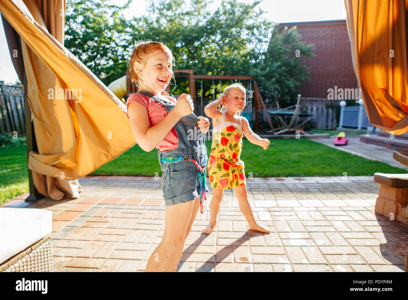 Portrait of two little girls sisters having fun on home backyard ...