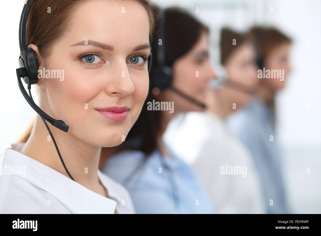 Call center. Beautiful cheerful smiling operator consulting clients with headset. Business ...
